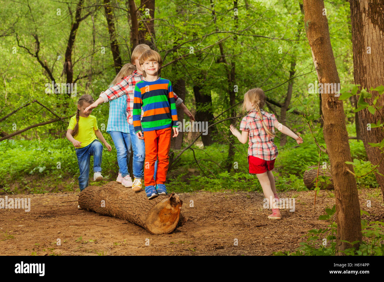 Cute little kids walking on log of tree in park Stock Photo - Alamy