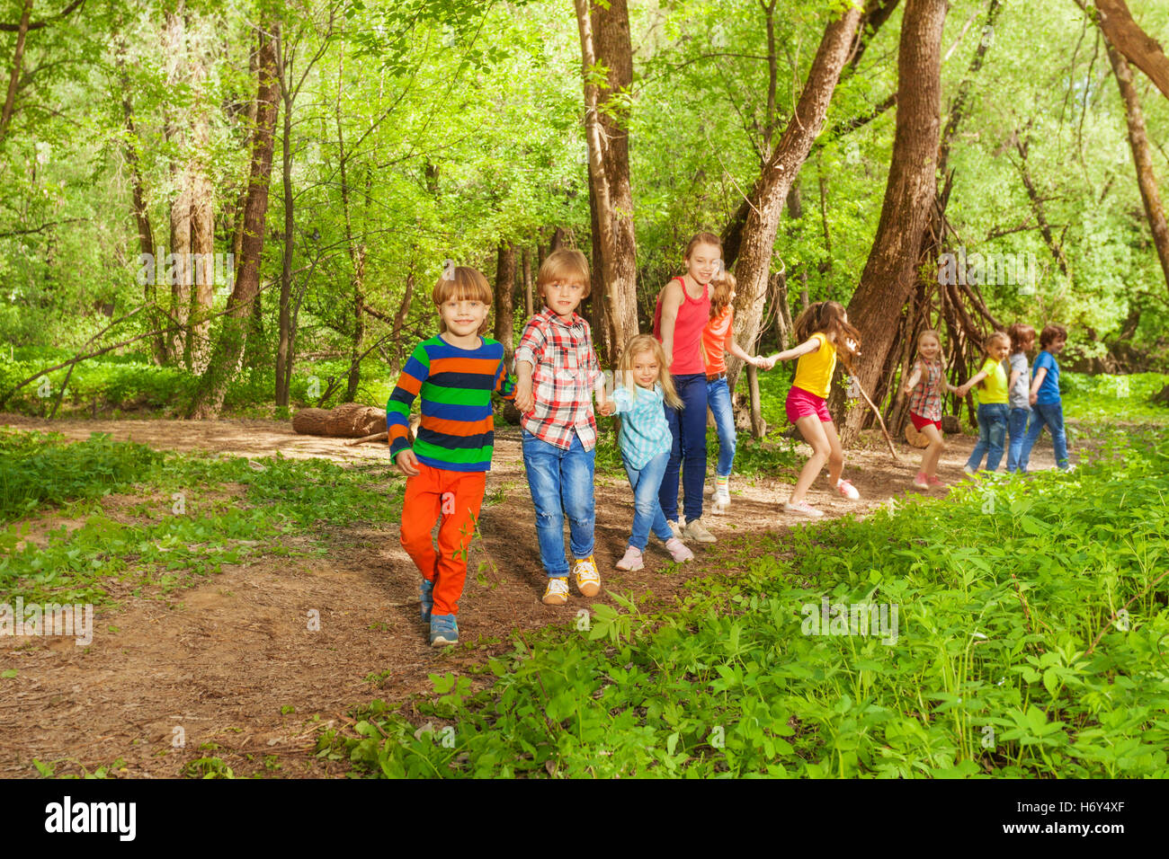 Happy kids walking together holding hands in park Stock Photo - Alamy
