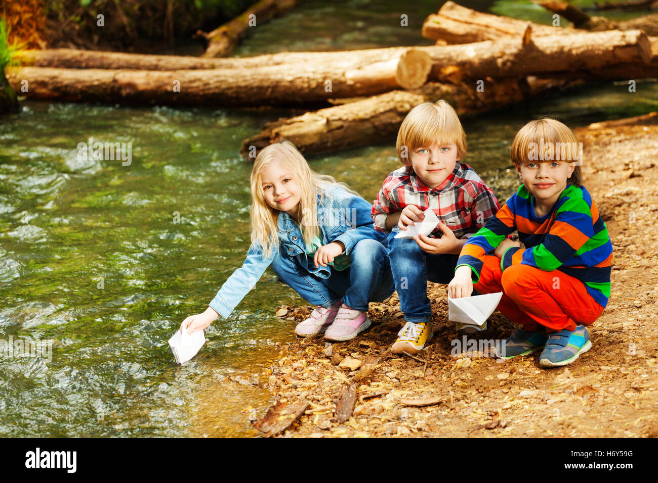 Happy kids playing with paper boats at river bank Stock Photo - Alamy