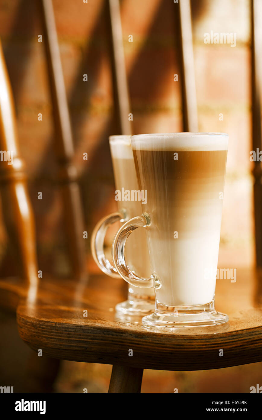 latte coffee in tall glasses on vintage chair with old brick wall ...