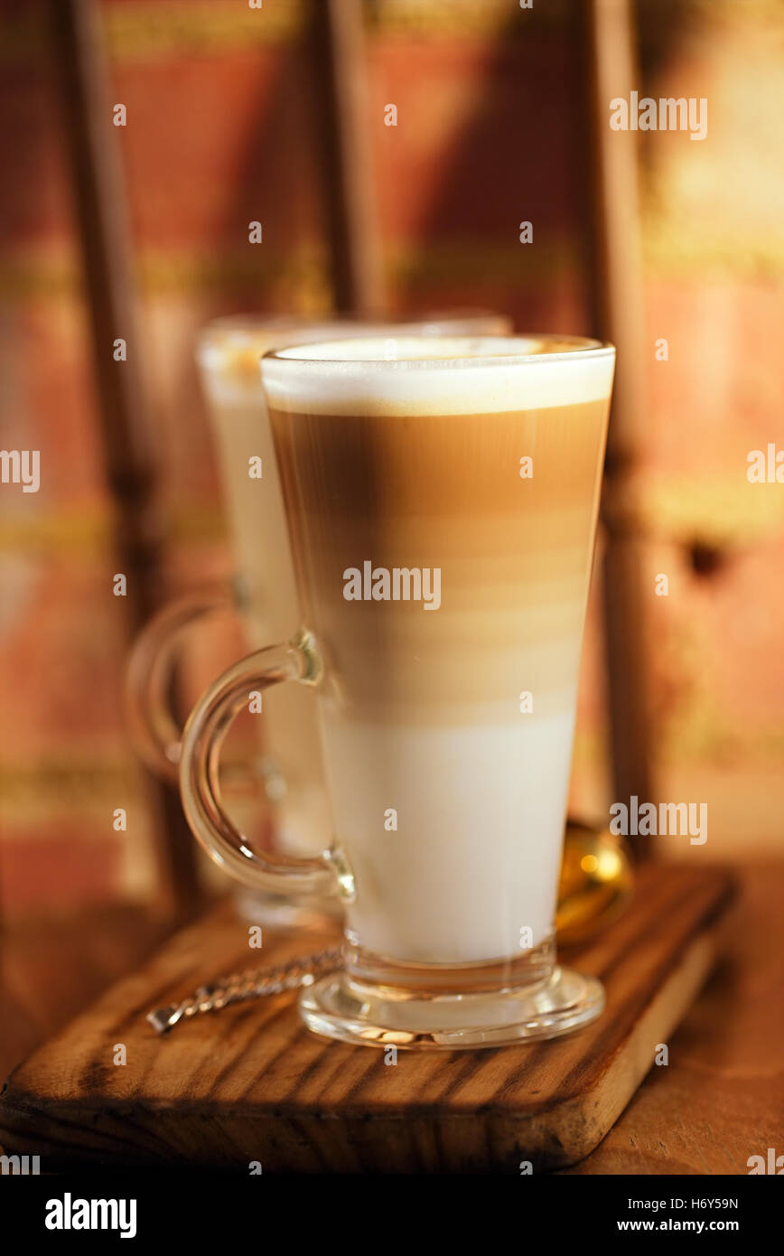 latte coffee in tall glasses on vintage chair with old brick wall ...