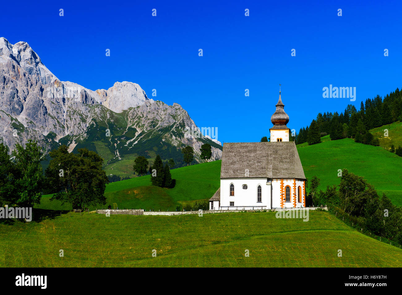 Beautiful little church in Alps. Sunny day, green grass on the hill and ...