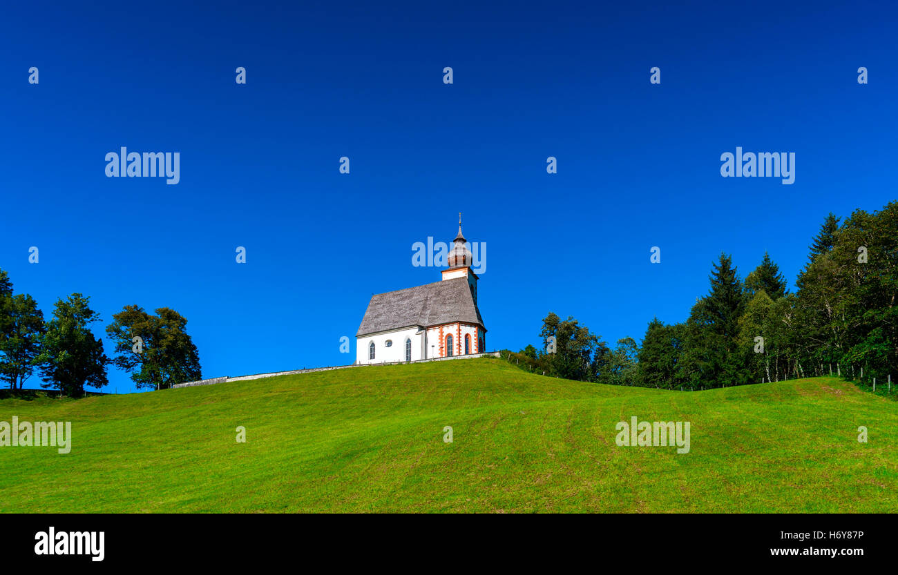 Beautiful little church in Alps. Sunny day, green grass on the hill and ...