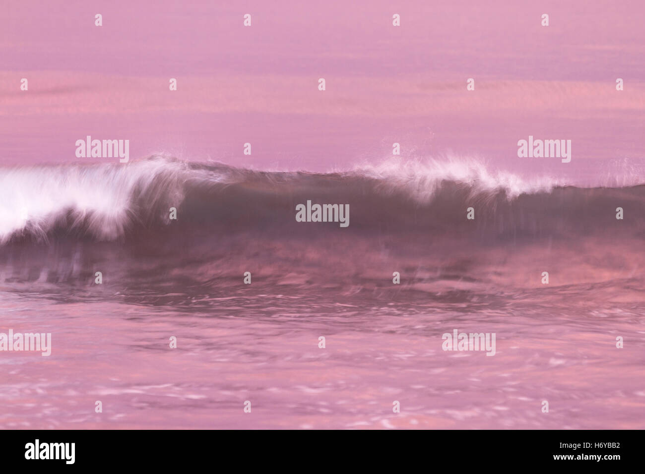 sunset glow used for lighting with a slow shutter speed on moving waves ...