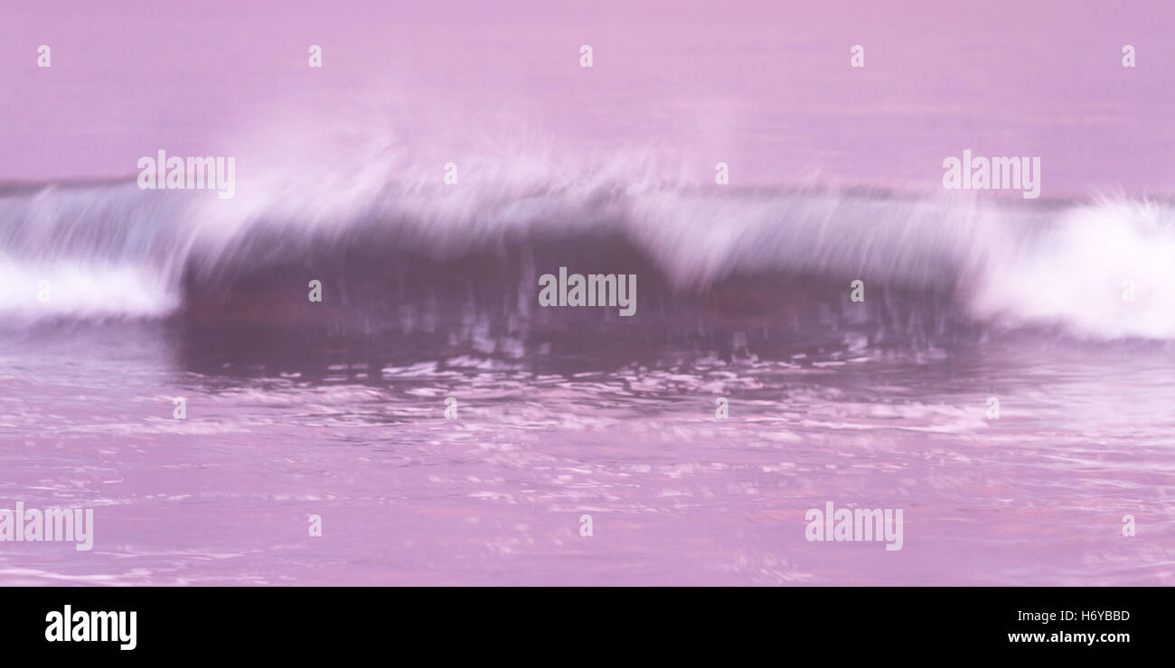 sunset glow used for lighting with a slow shutter speed on moving waves ...