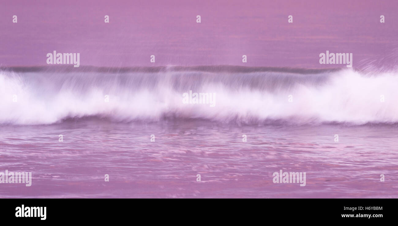 sunset glow used for lighting with a slow shutter speed on moving waves ...