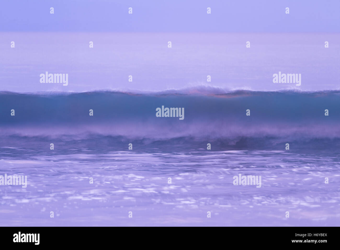 sunset glow used for lighting with a slow shutter speed on moving waves ...