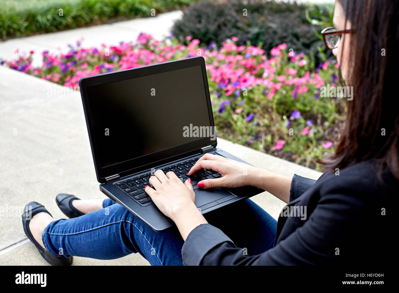 A pretty young woman with hands on the keyboard of a laptop computer ...