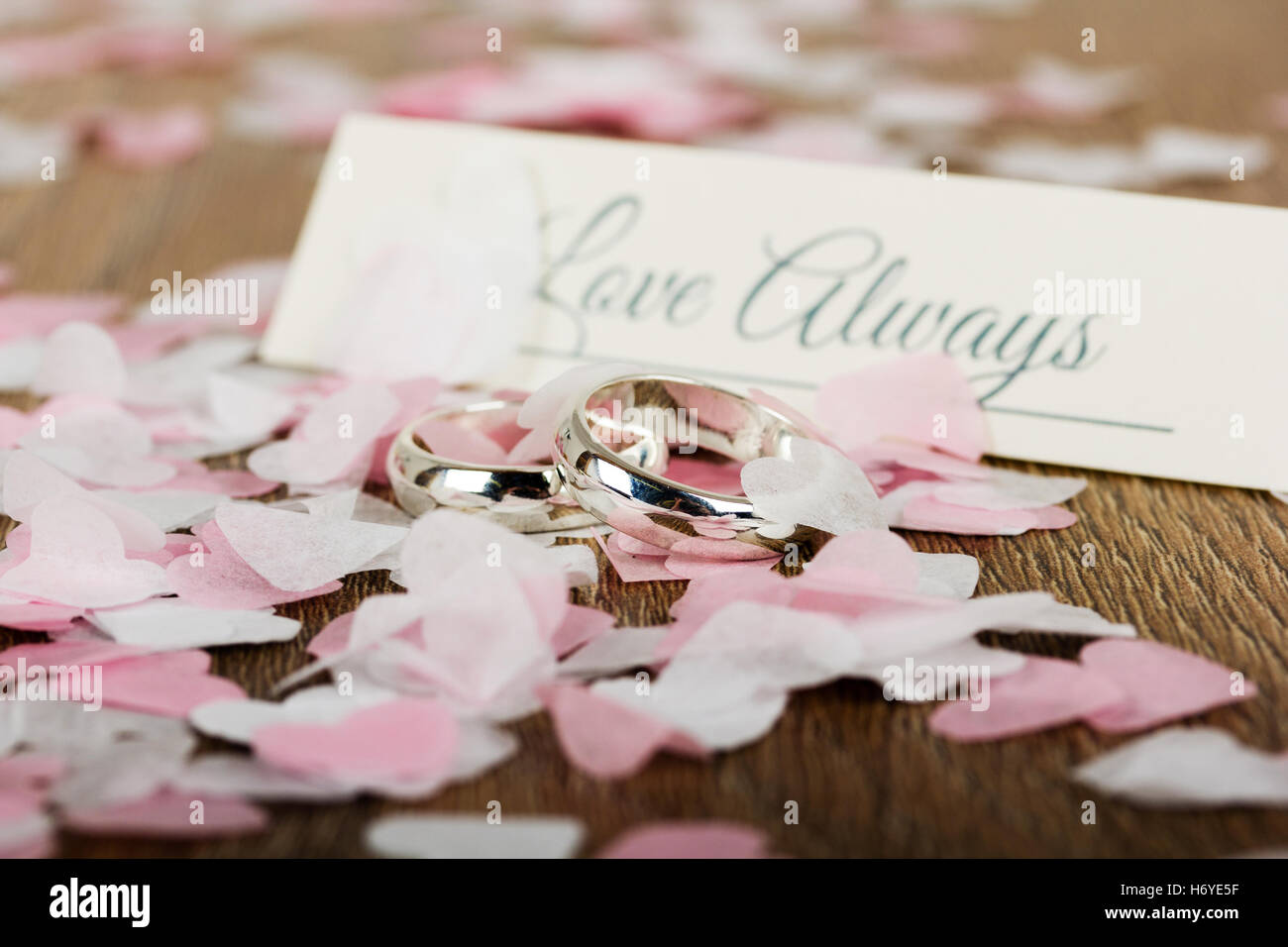 pair of white gold wedding rings on a wooden background with confetti ...