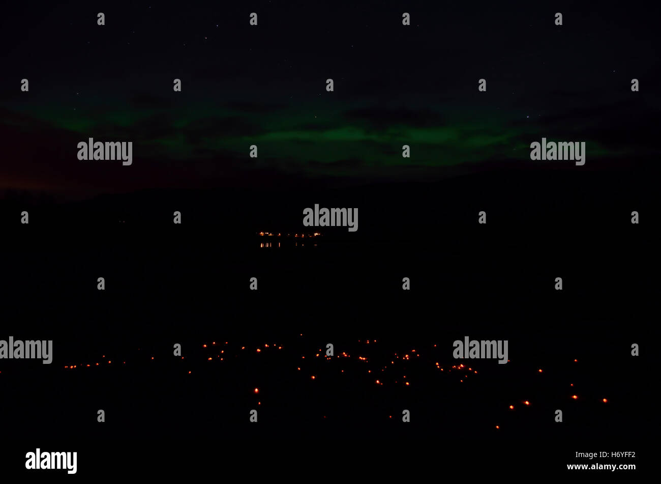 red glowing embers on river ice at night with aurora borealis on sky ...