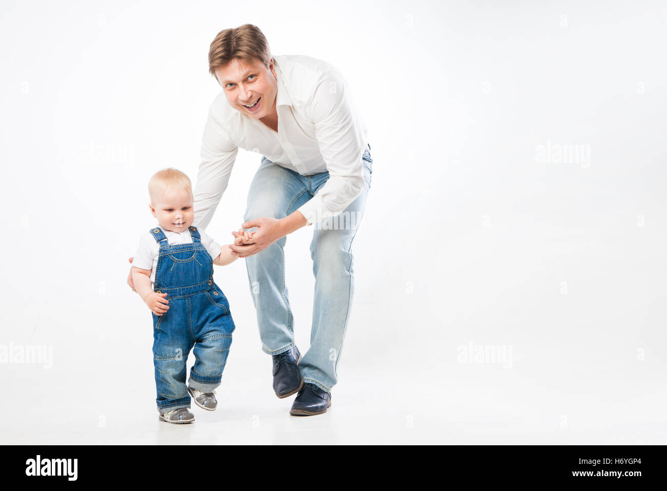 Man looking at camera and holding toddler's hand while baby is making ...