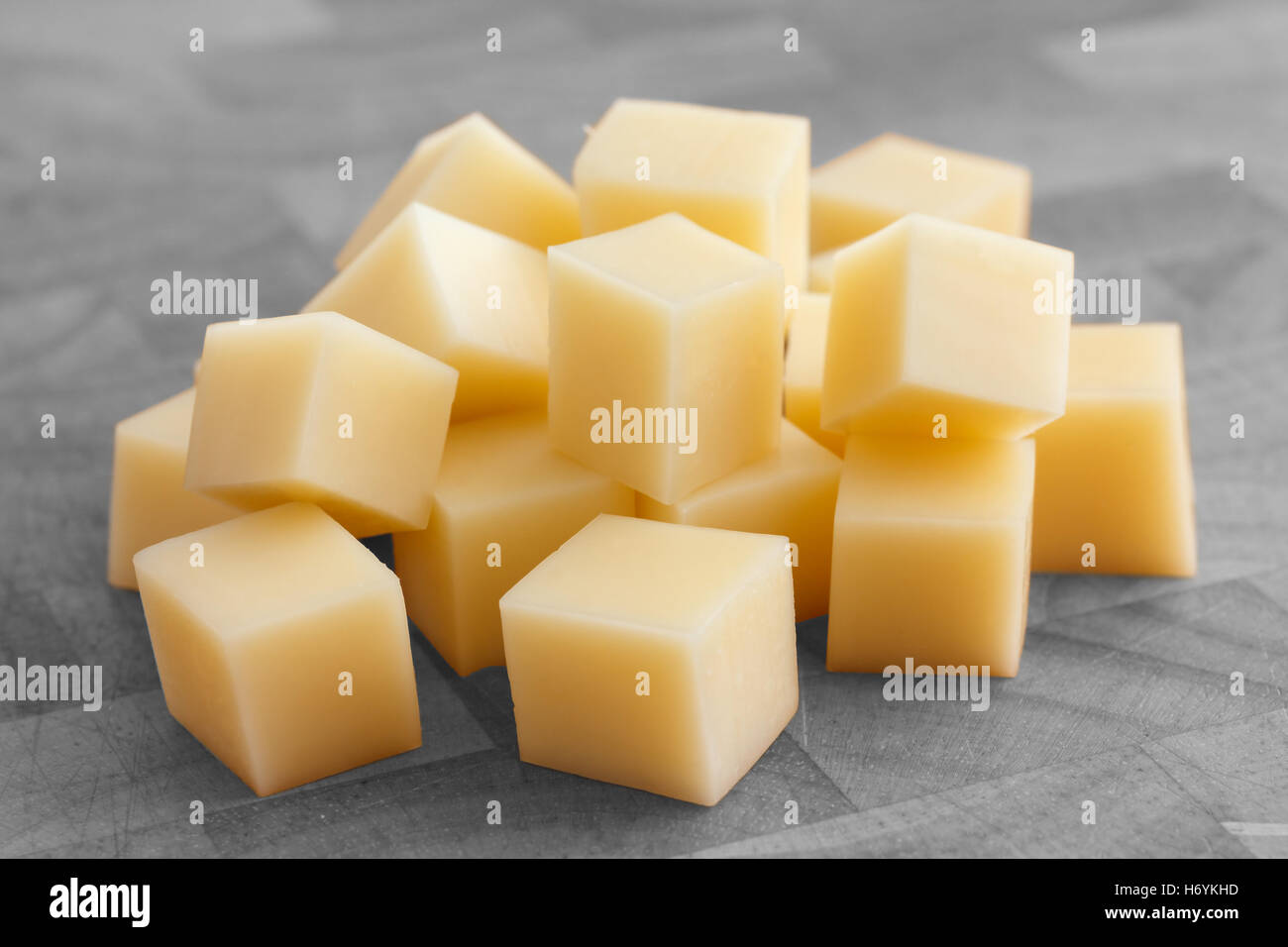 Cubes of yellow cheese stacked randomly on wood chopping board Stock ...
