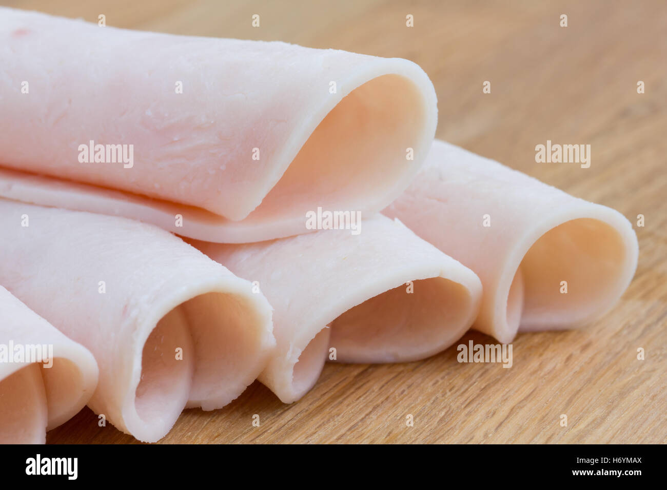 Rolled slices of ham on a wood surface Stock Photo - Alamy