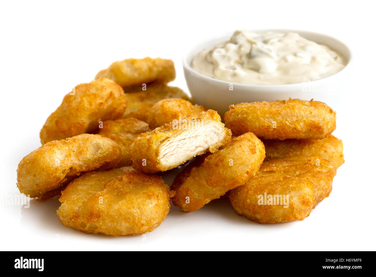 Pile of golden deep-fried battered chicken nuggets with bowl of tartar ...