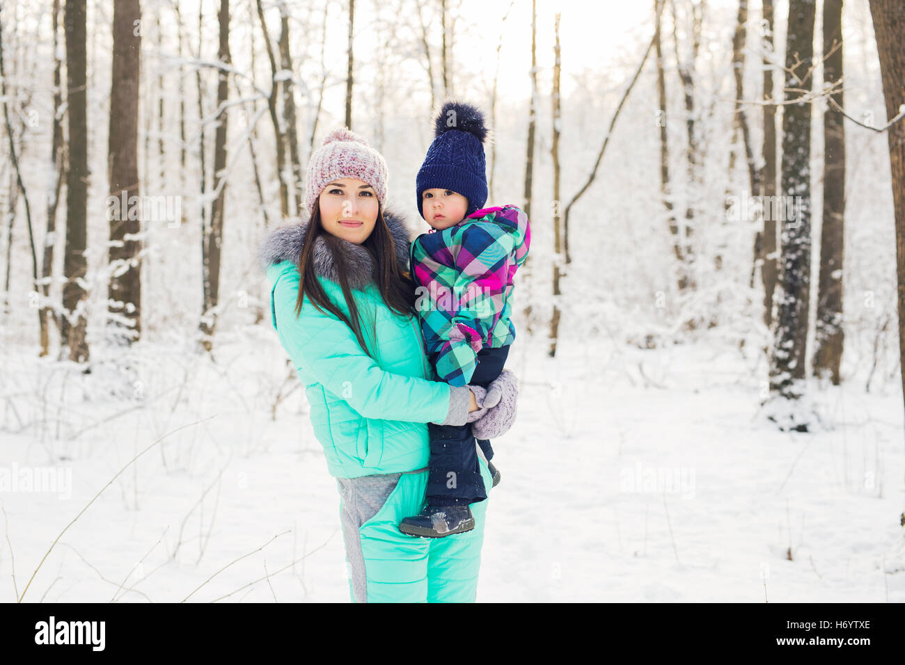 happy family mother and baby girl daughter playing and laughing in winter outdoors in the snow ...