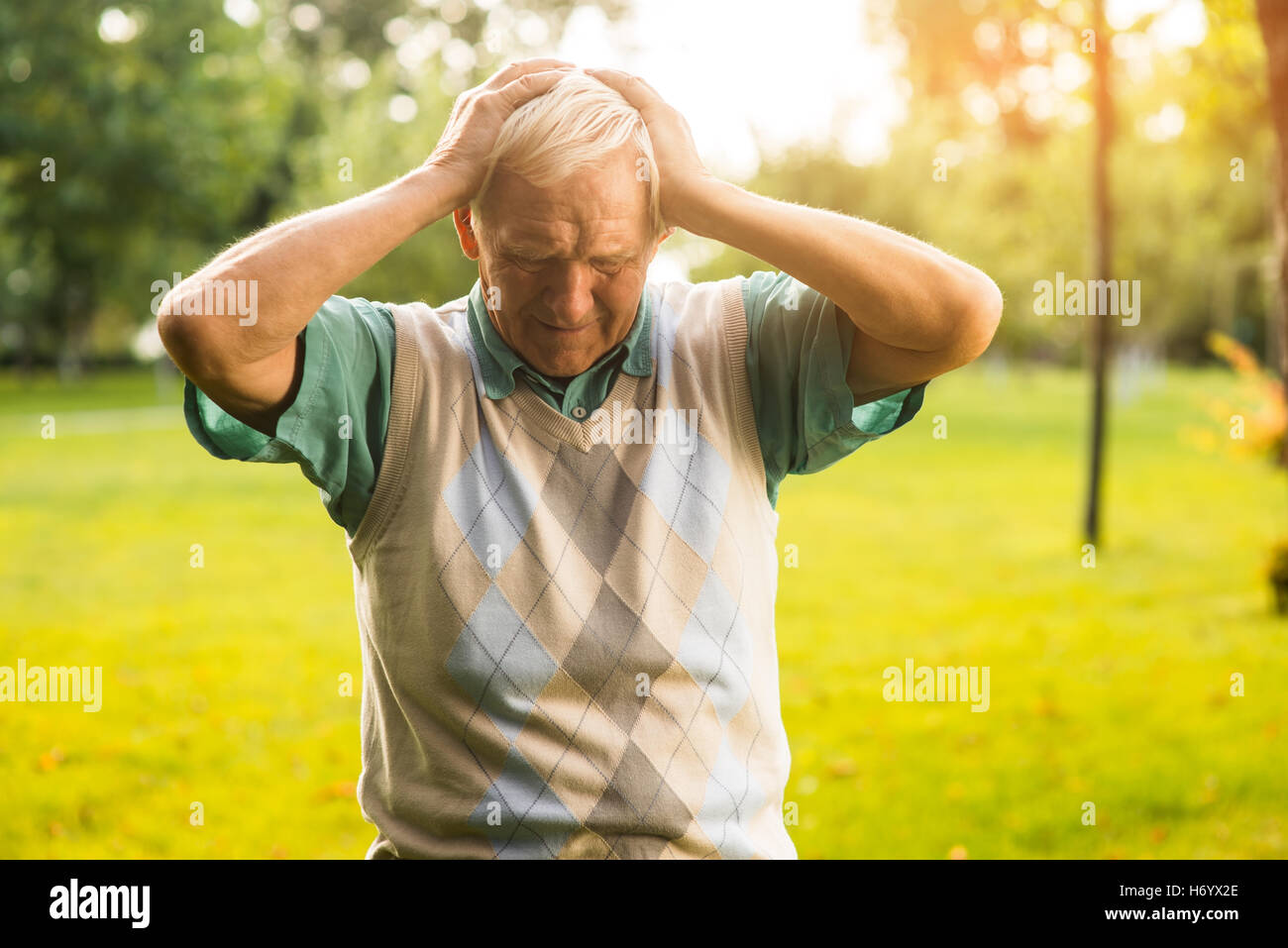 Senior man holding his head Stock Photo - Alamy