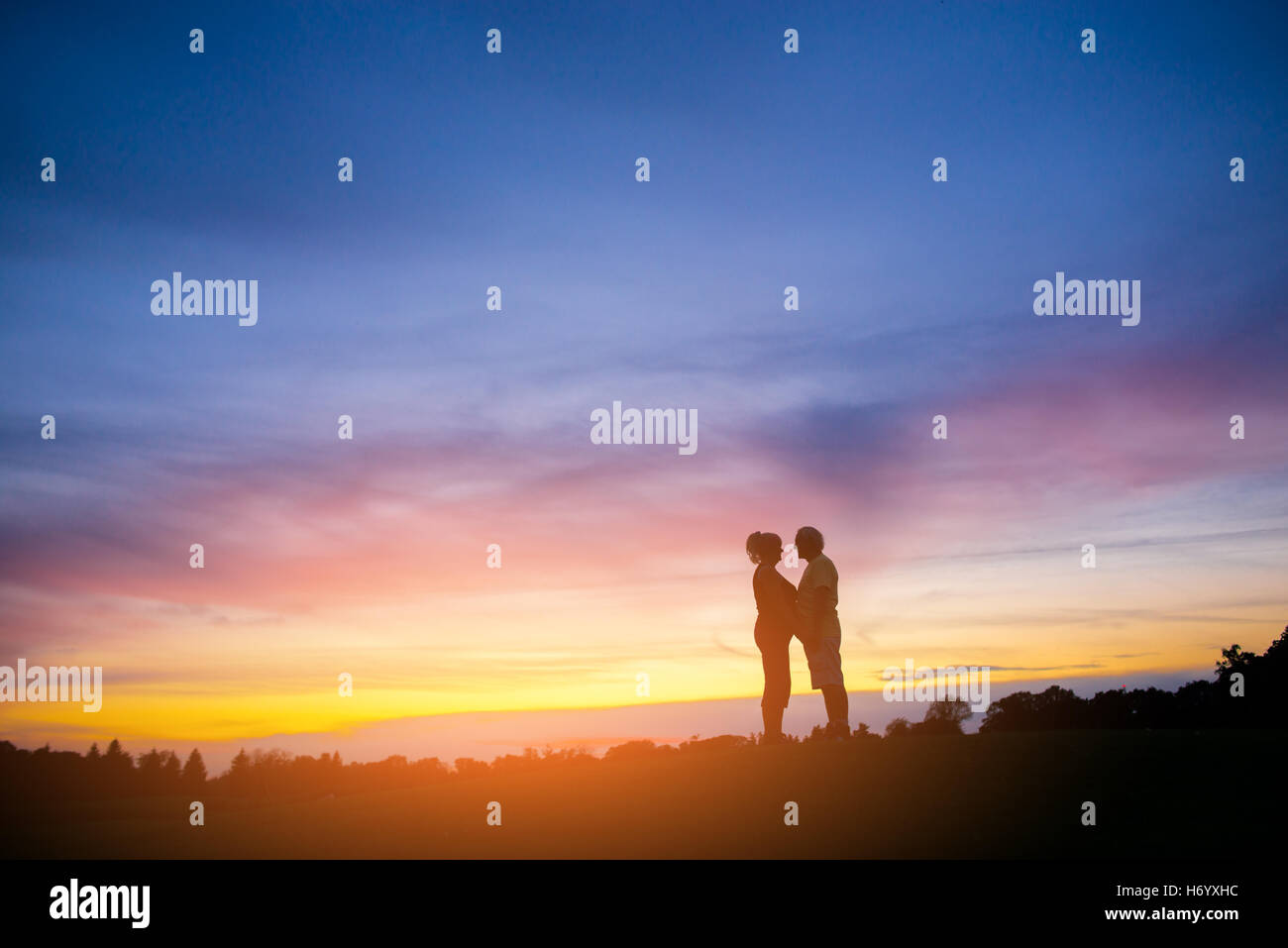Couple standing on sunset background Stock Photo - Alamy