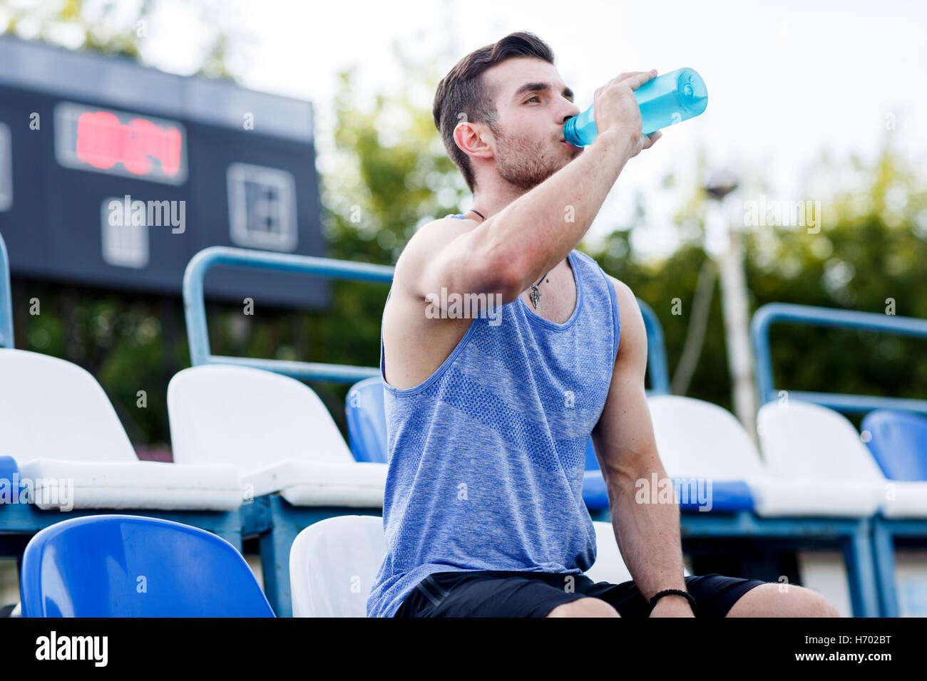 Fitness sports man in blue shirt drinking water after exercising on ...