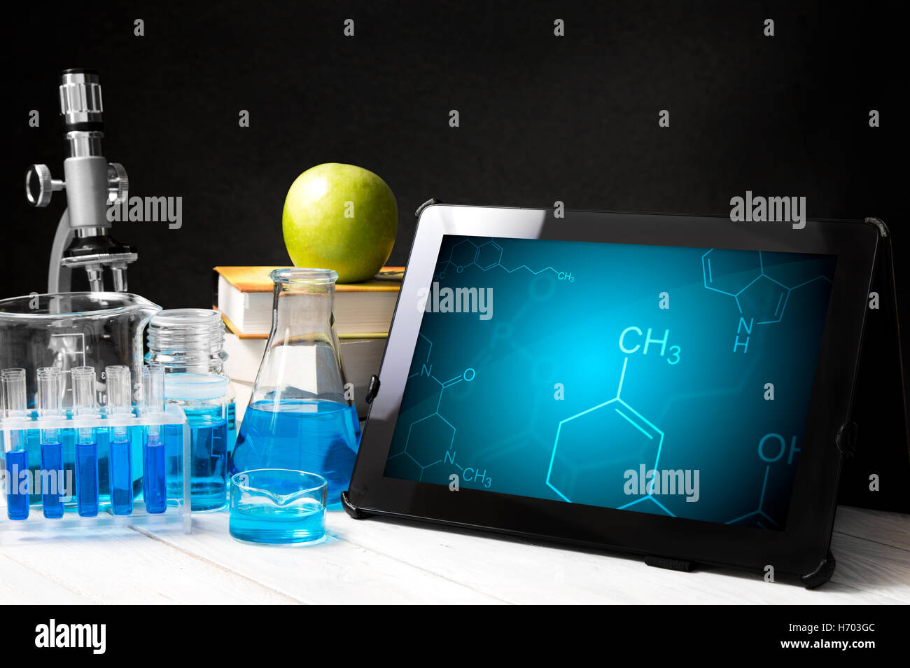Tablet with chemistry symbols on the desk and scientific school ...