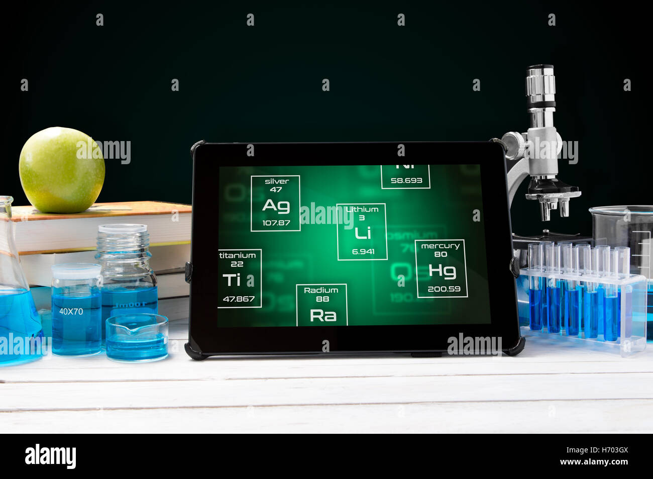 Tablet with periodic table symbols on the desk with scientific school ...