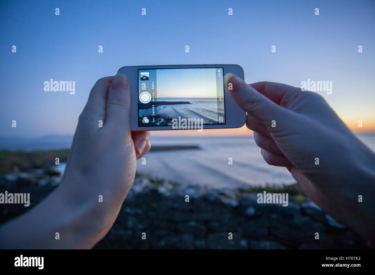 Hands using a smart phone to take a photograph of a landscape at ...