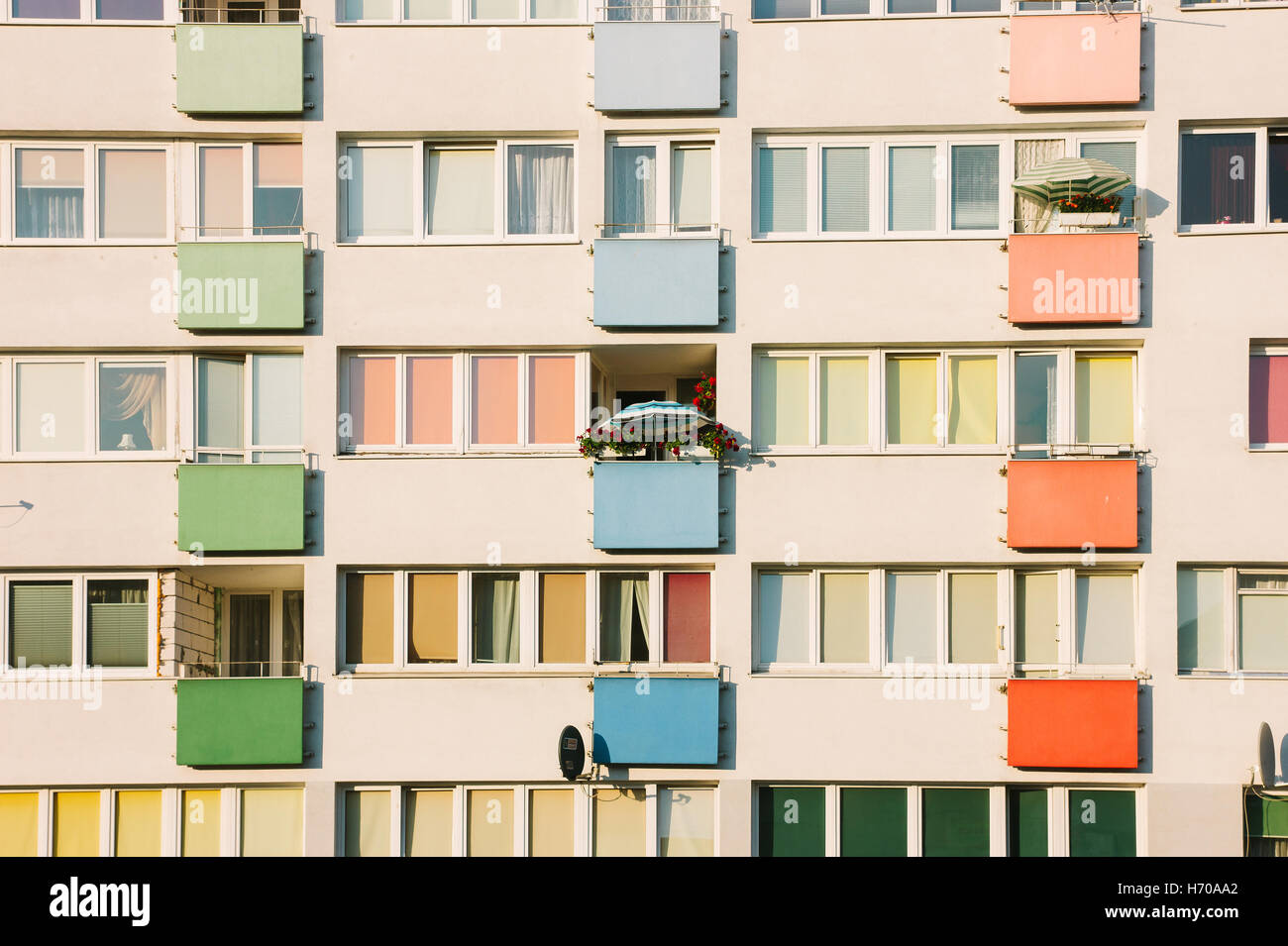 The facade of a pale pink apartment building with colorful balconies ...