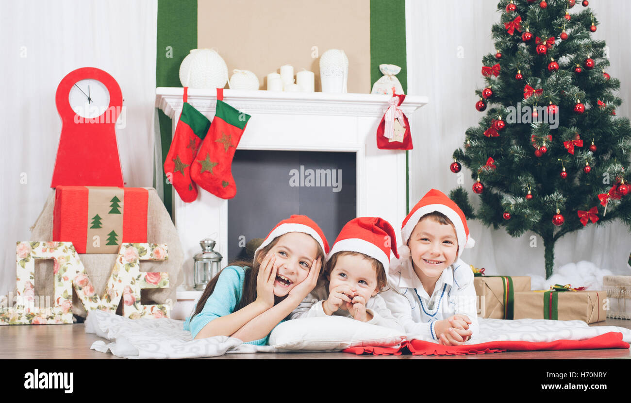 three happy children in santa hats smiling on background of Christmas ...