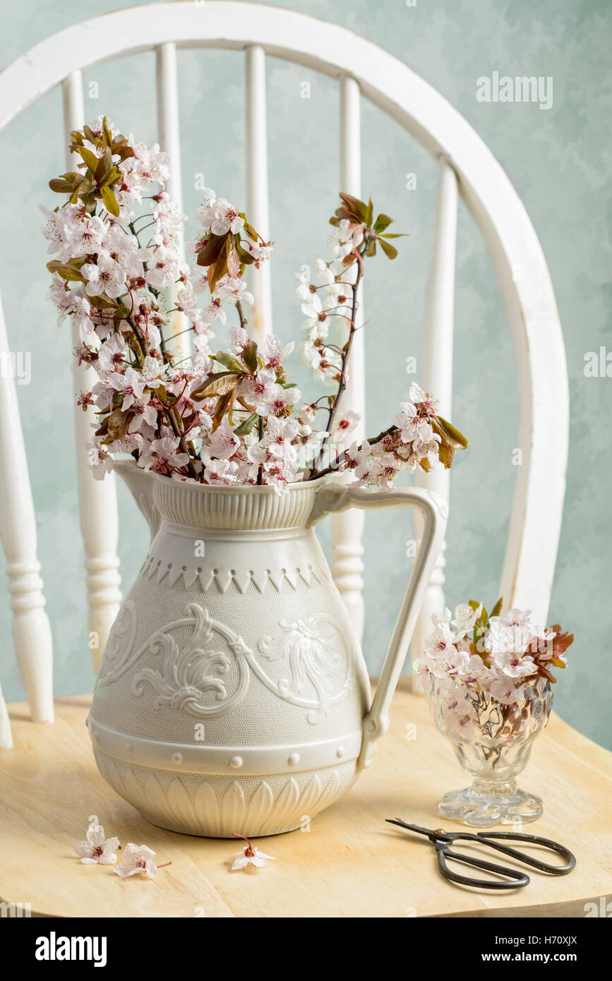 Spring blossom in antique pottery vase with scissors on rustic chair ...
