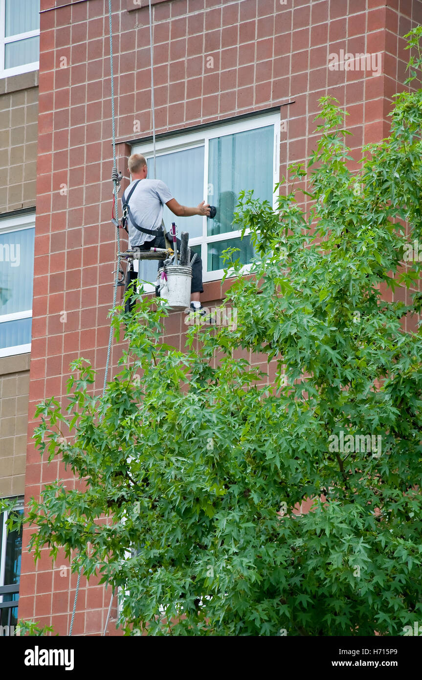 A man is washing windows in a tall building in this vertical image ...