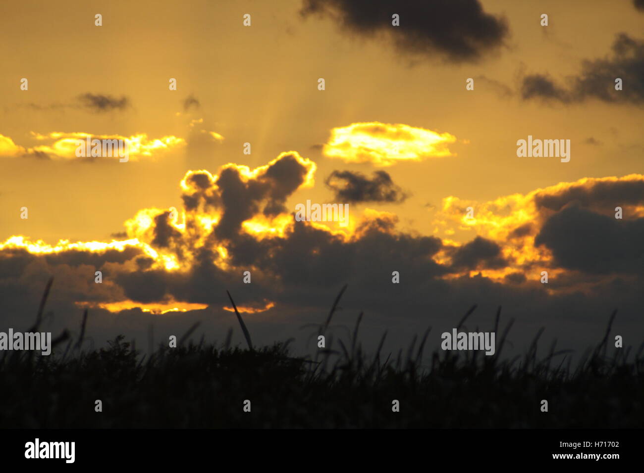 Sun setting behind some clouds at the end of a rainy day giving the ...