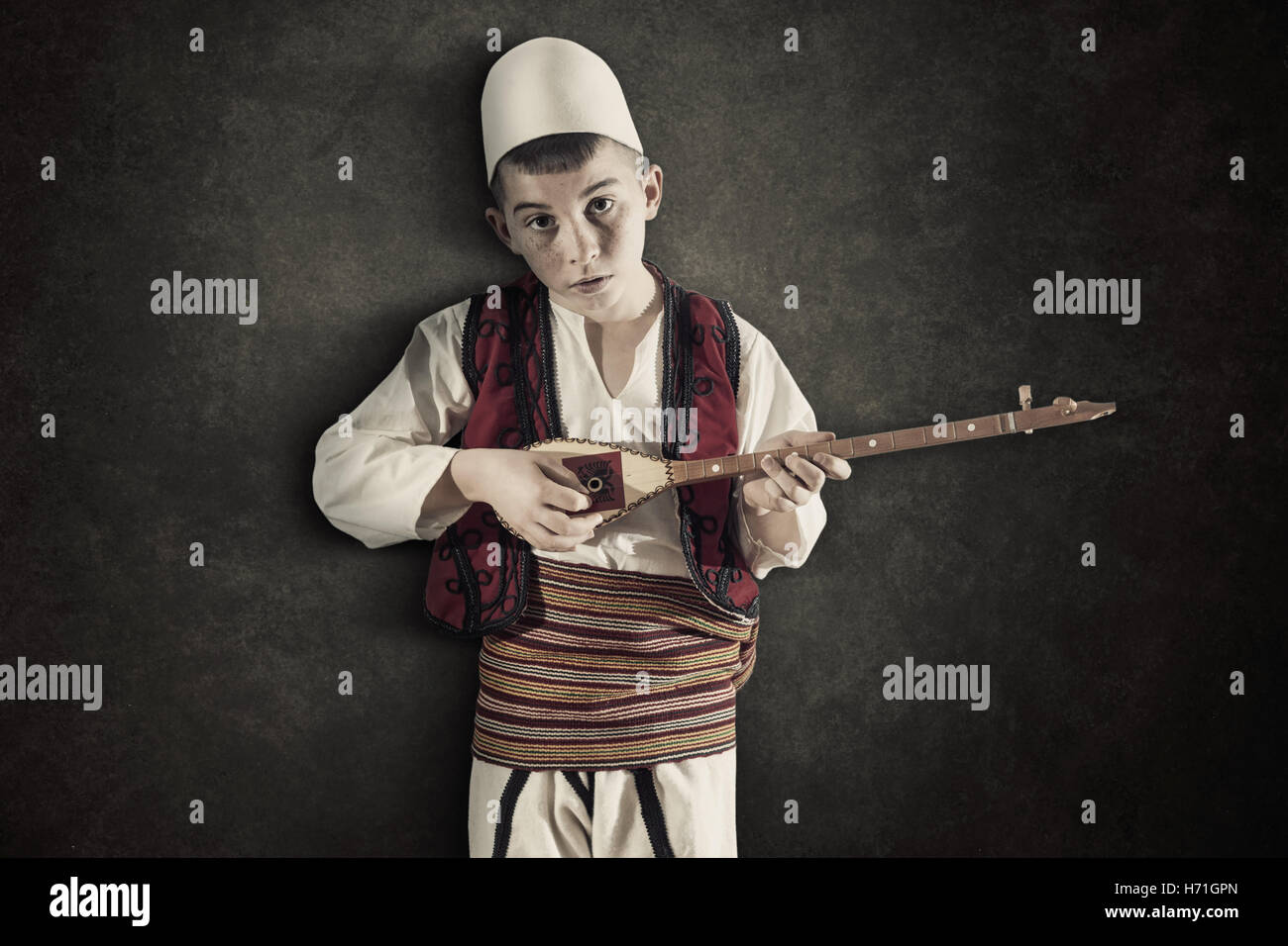 young boy in traditional albanian costume playing traditional string ...