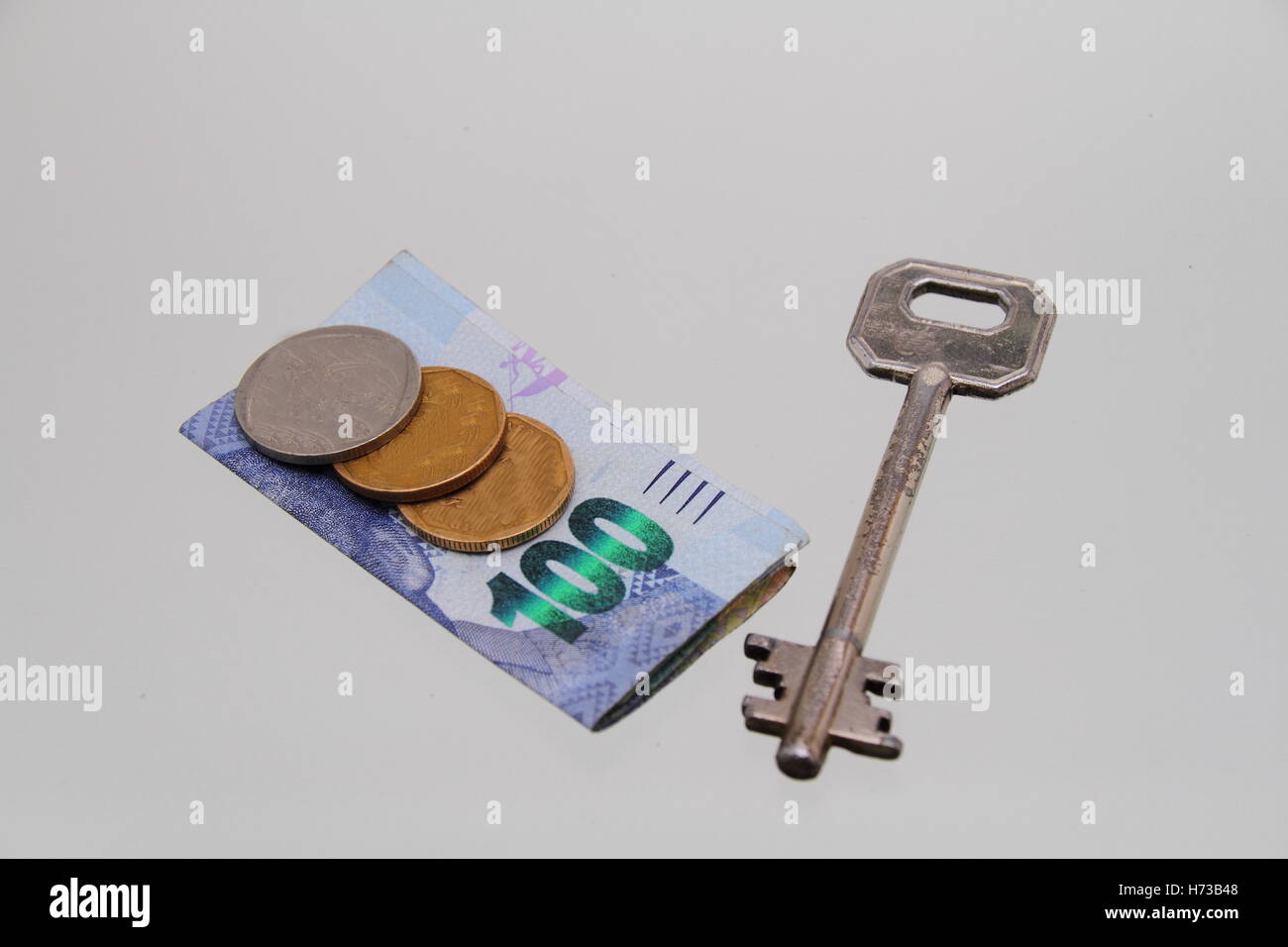 A metal key and cash money isolated on a white background image with ...