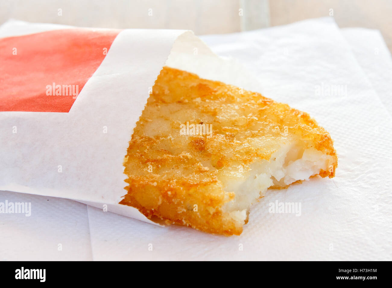 Single partially eaten hash brown in paper bag on white napkin Stock ...