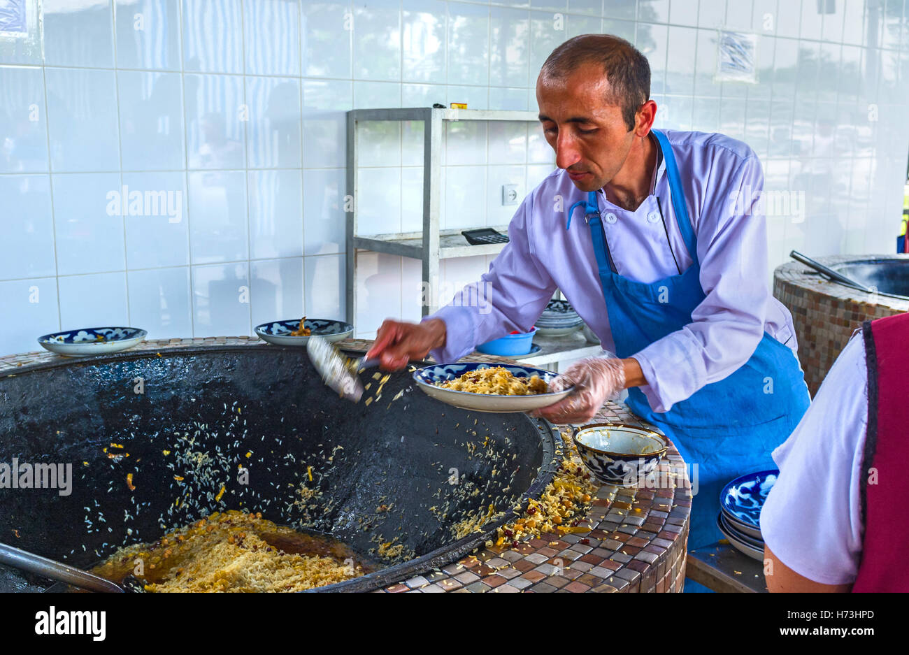 The chef puts the pilaf to the plate from the qozon Stock Photo - Alamy