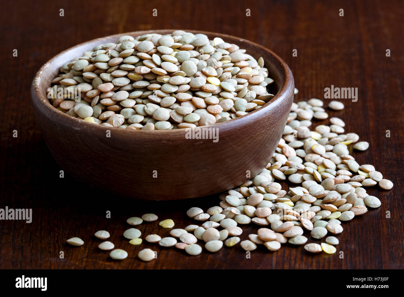 Rustic bowl of green uncooked lentils isolated on dark wood in ...
