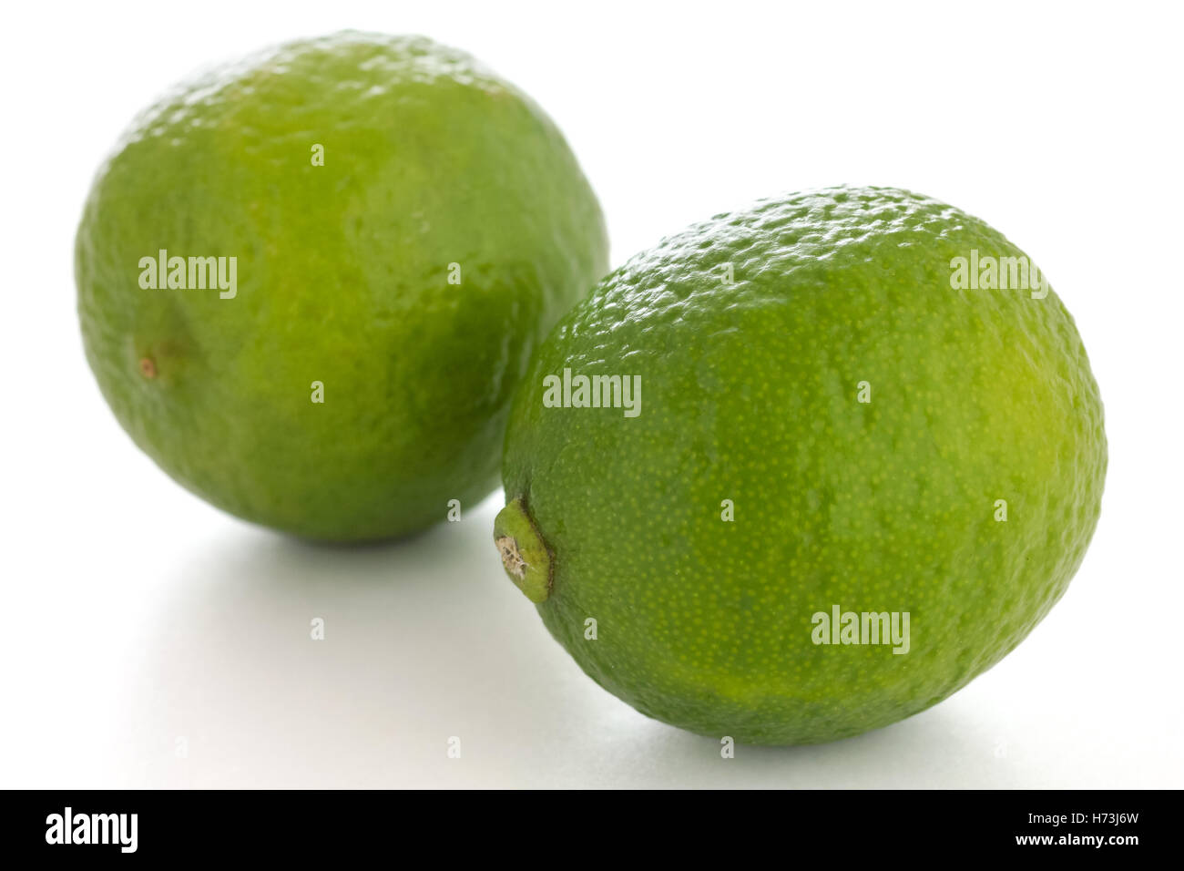 Two whole limes on a white surface Stock Photo - Alamy