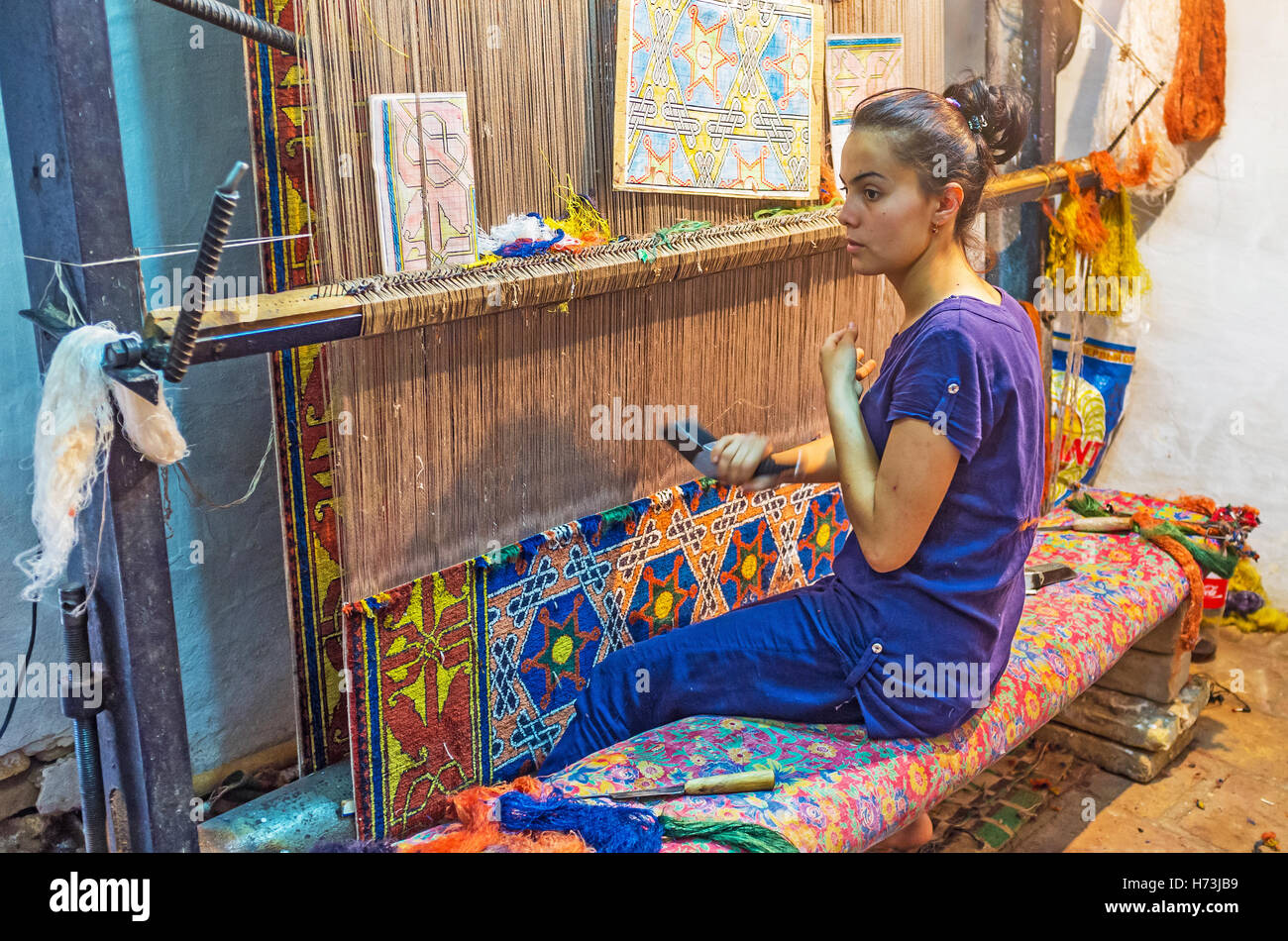 The teenage girl weaves the traditional Uzbek rug in the workshop Stock ...