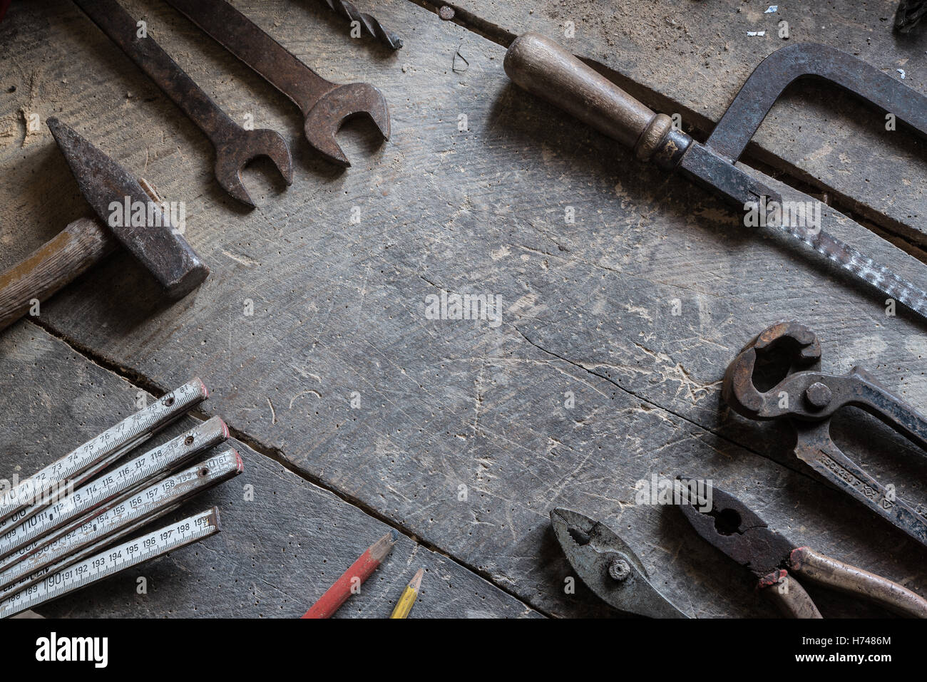 Old tools on the old workshop, wooden table, hummer, measure, saw ...