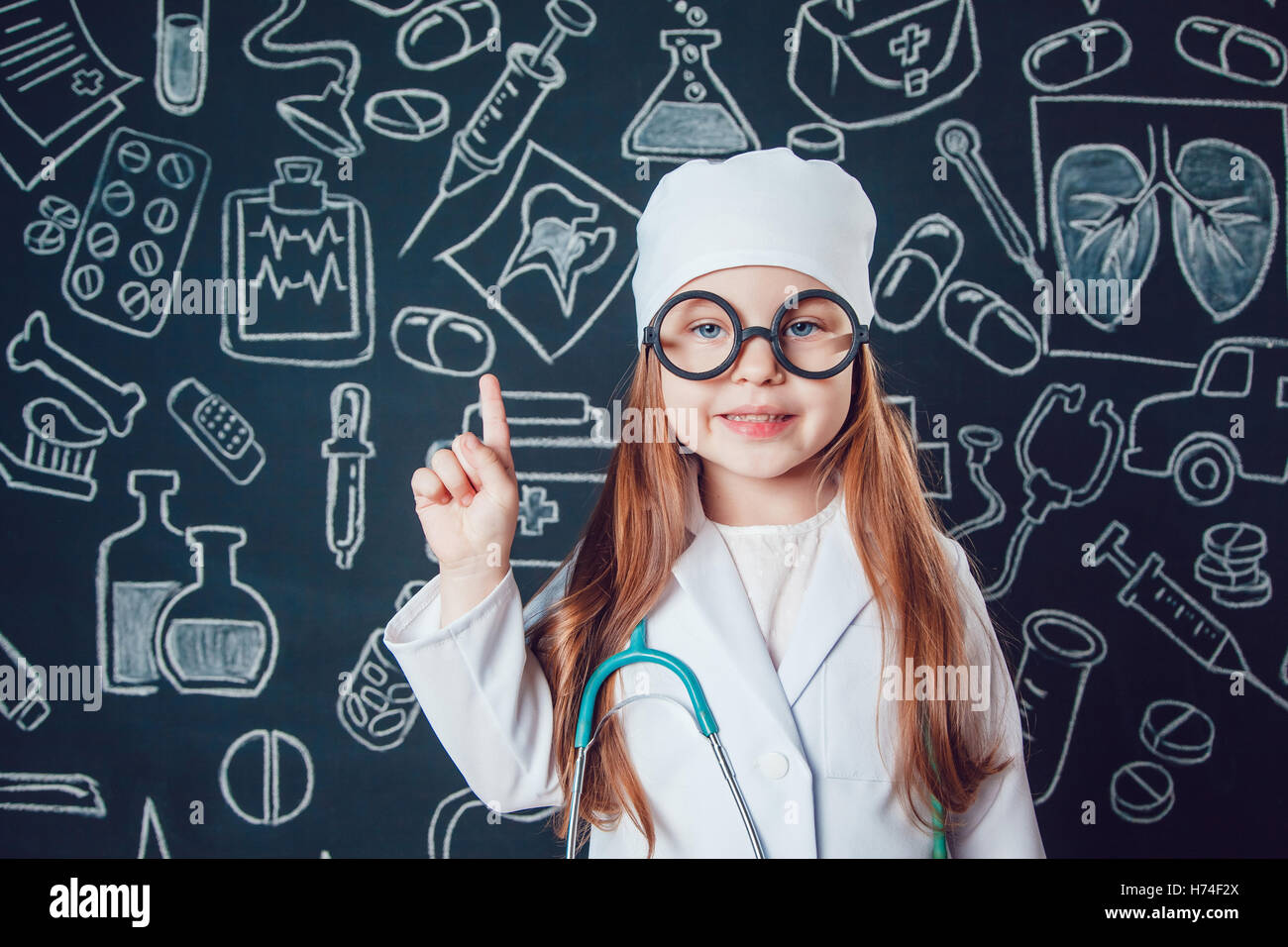 Happy little girl in doctor costume holding sthetoscope on dark ...