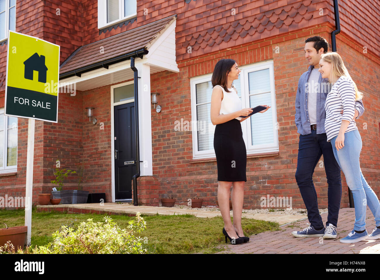Realtor Outside House For Sale With Young Couple Stock Photo - Alamy