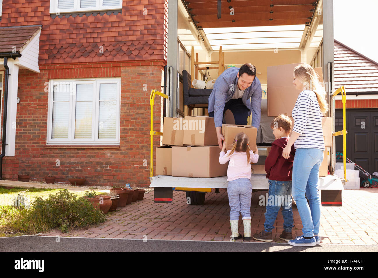 Family Unpacking Moving In Boxes From Removal Truck Stock Photo - Alamy