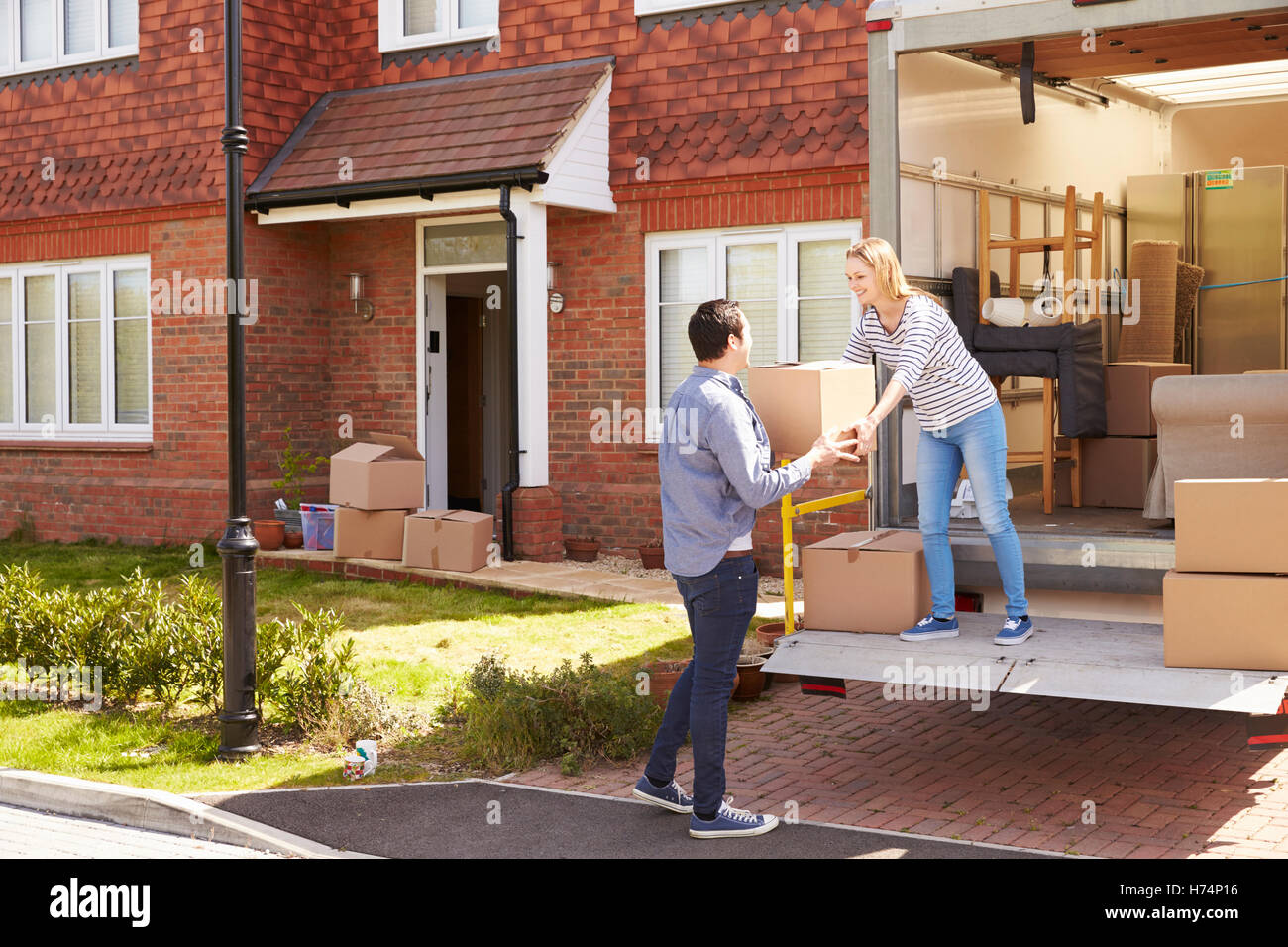 Couple Unpacking Moving In Boxes From Removal Truck Stock Photo - Alamy