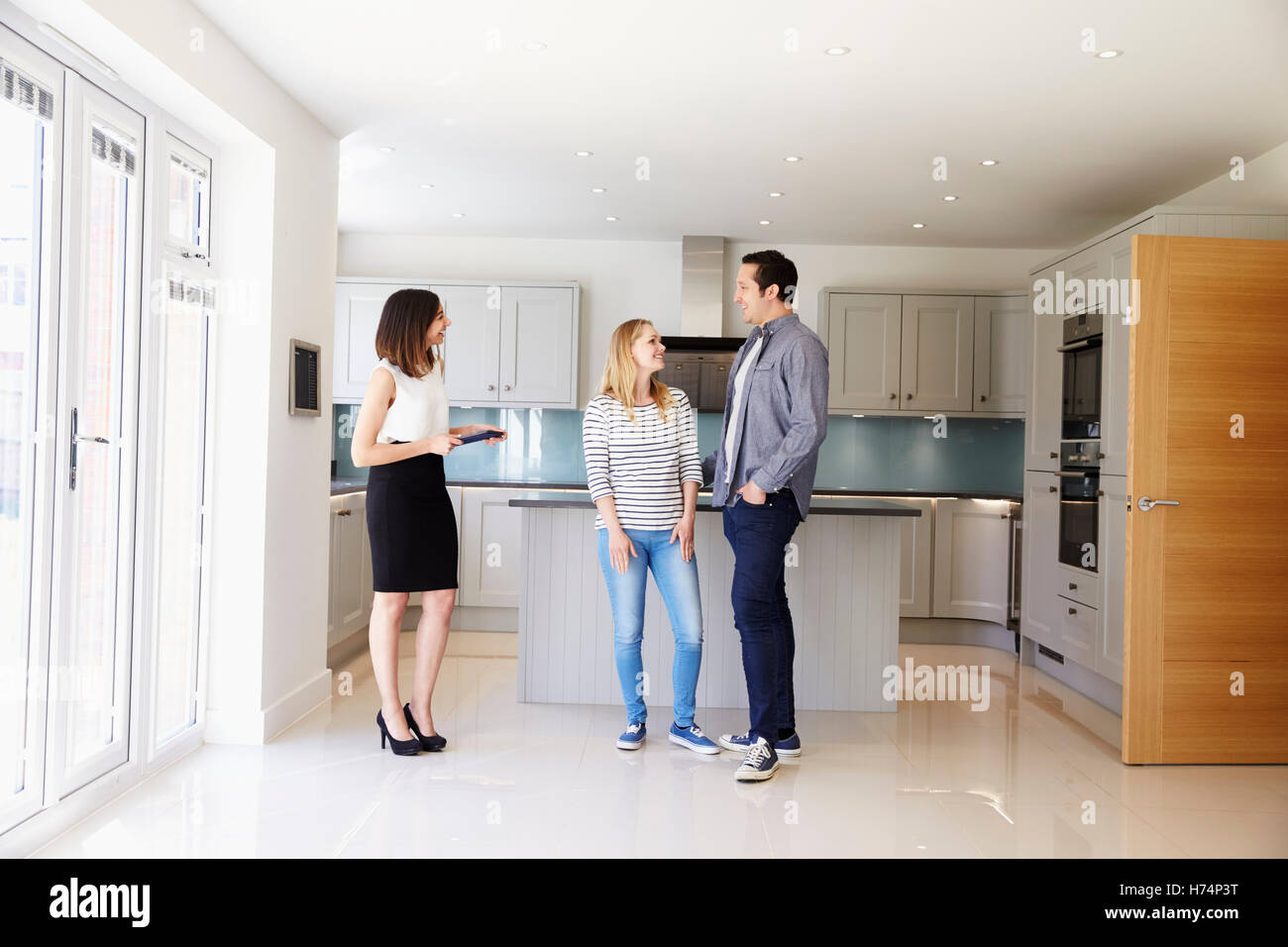 Realtor Showing Young Couple Around Property For Sale Stock Photo - Alamy