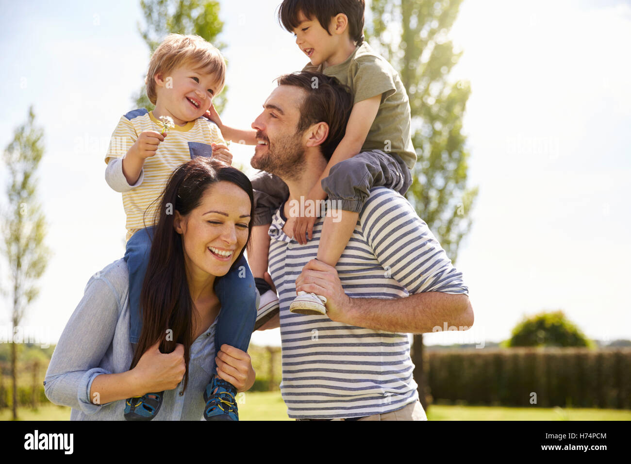 Parents carrying children on shoulders having fun hi-res stock ...
