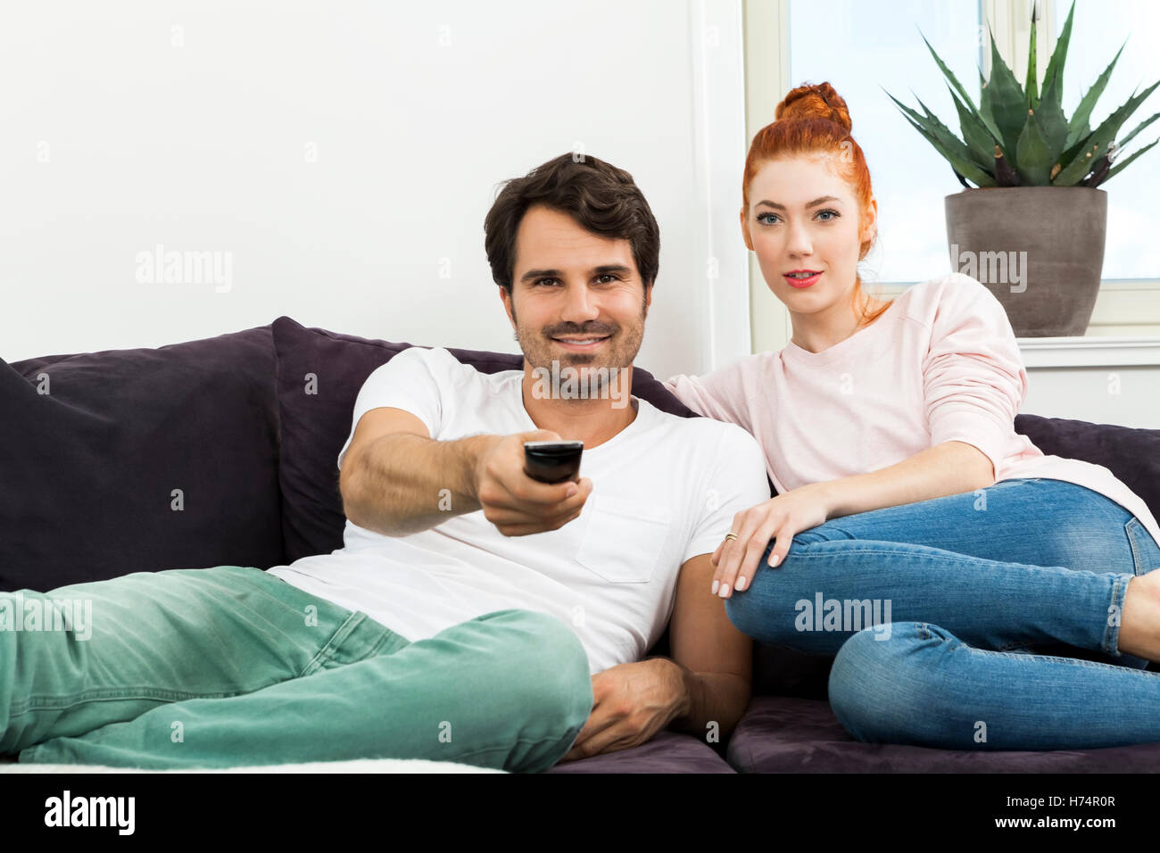 happy young couple sitting at home in the living room on the couch ...