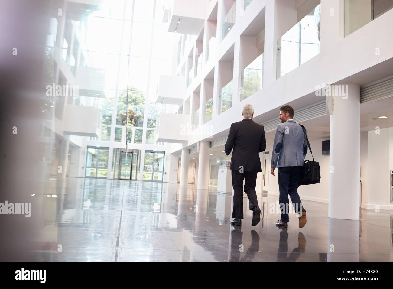 Rear View Of Businessmen Walking Through Office Lobby Stock Photo - Alamy