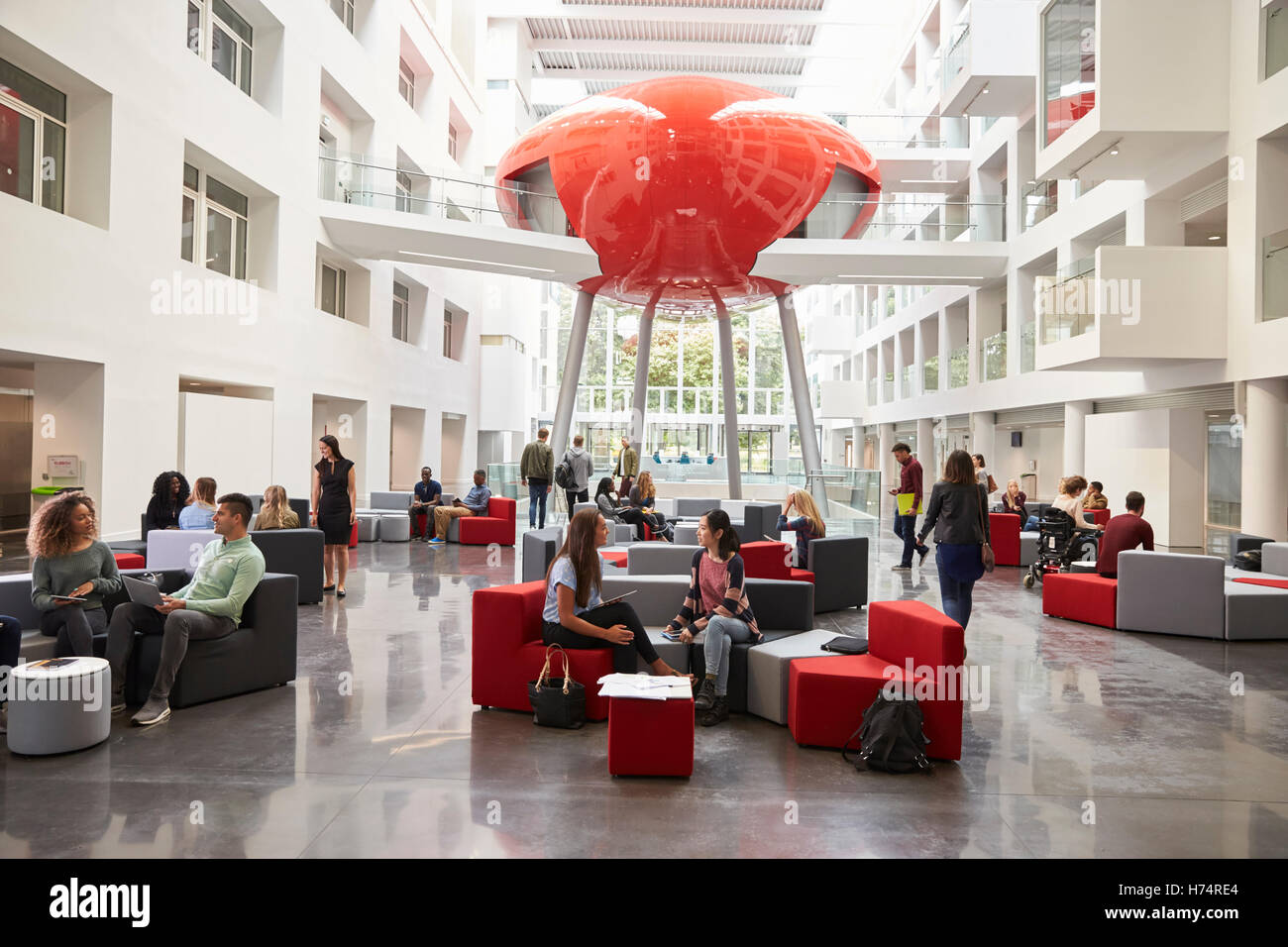 Students sit talking in the atrium lobby of their university Stock ...