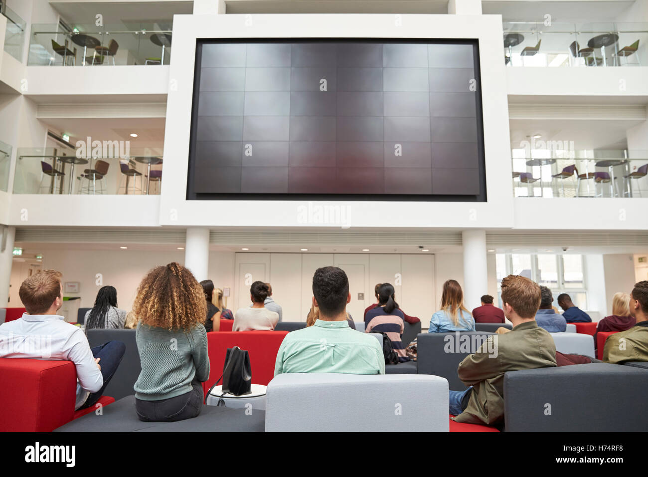 Students watching big screen in university atrium, back view Stock ...