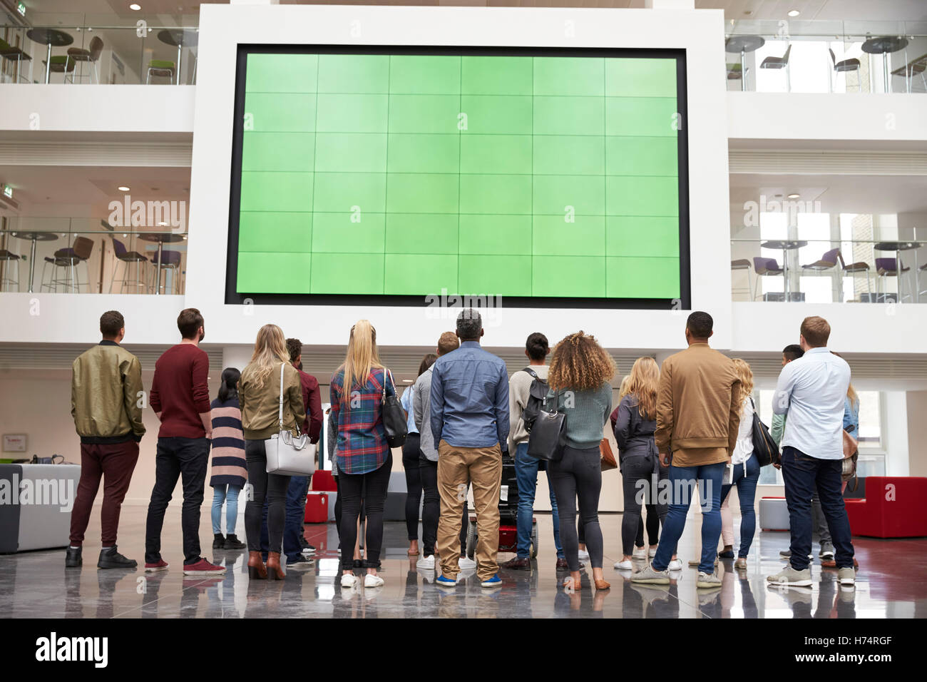 Students looking up at a big screen in university building Stock Photo ...