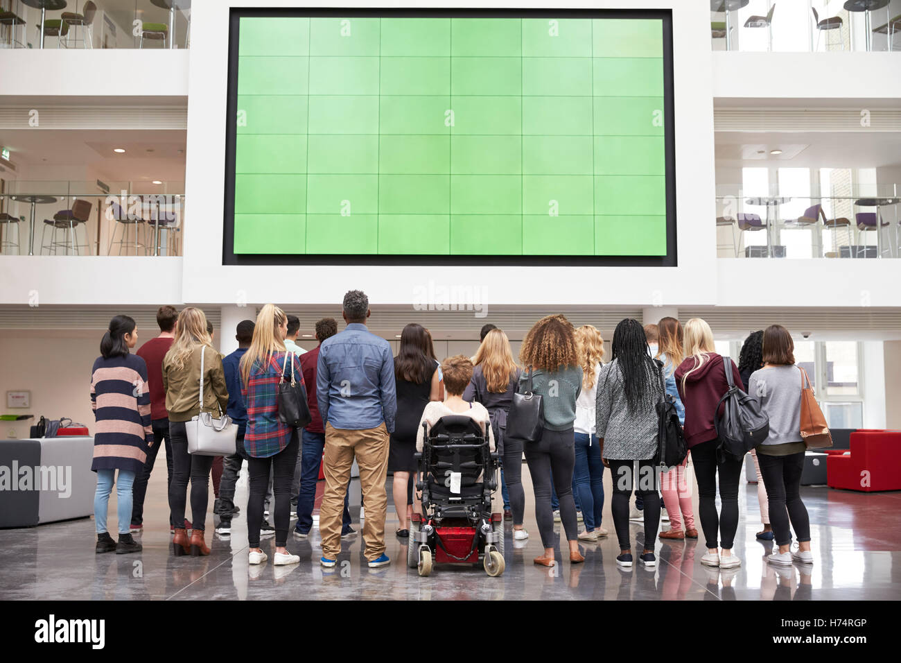 Students looking up at a big screen in university atrium Stock Photo ...